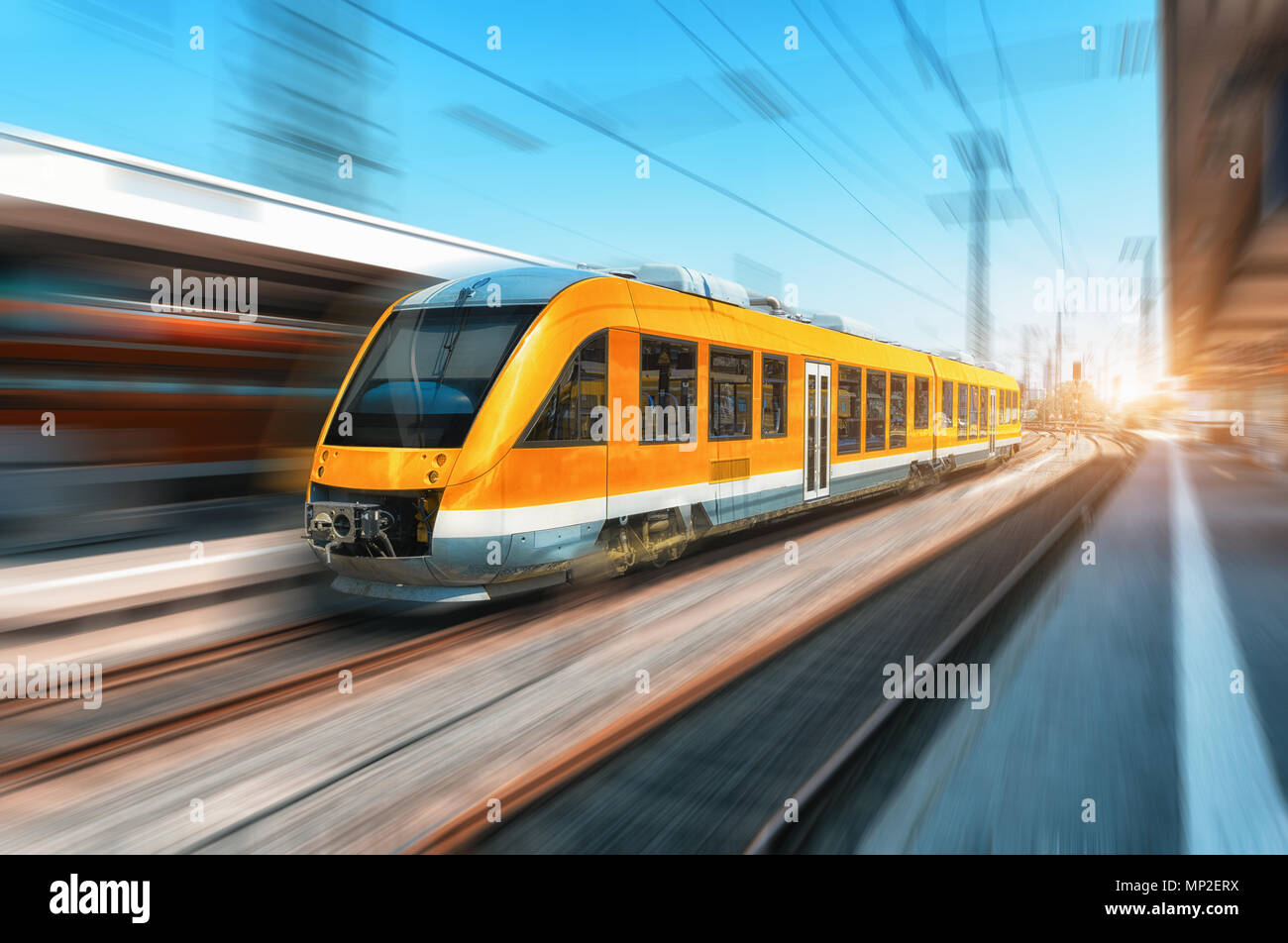 High speed orange train in motion on the railway station at bright day ...