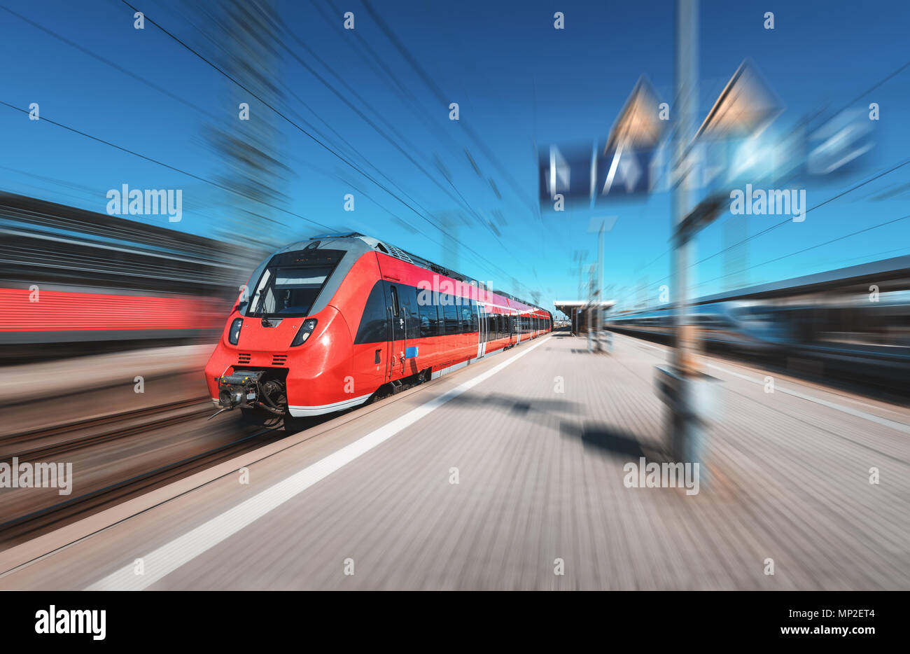 High speed red train in motion on the railway station at bright day ...