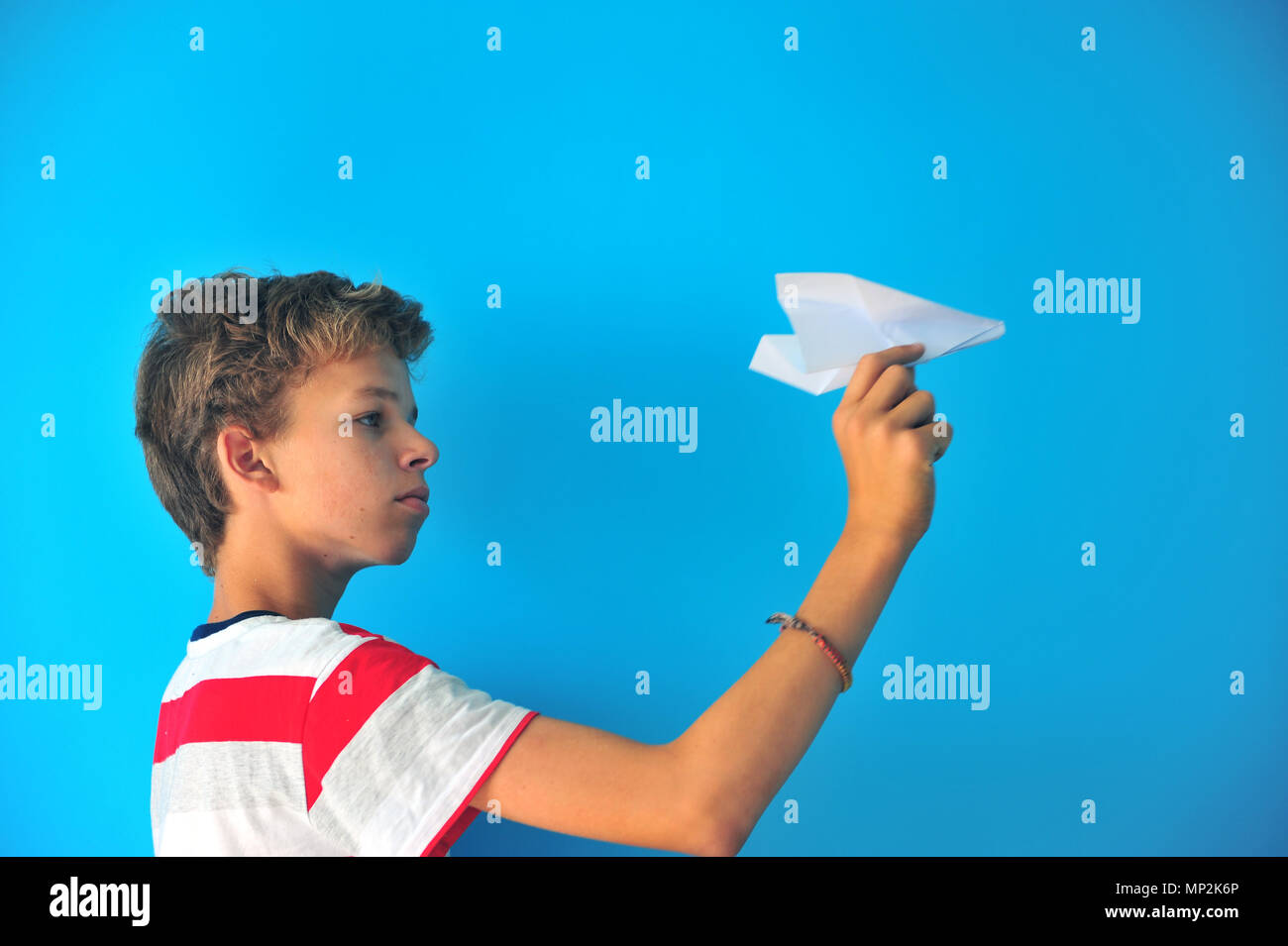 Boy with a paper airplane on blue background Stock Photo - Alamy