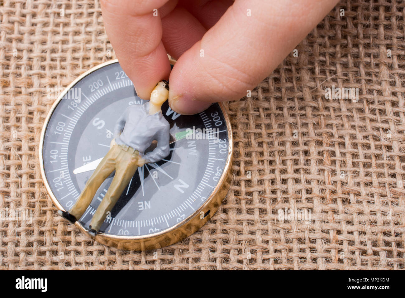 Hand holding a figurine beside a compass Stock Photo - Alamy