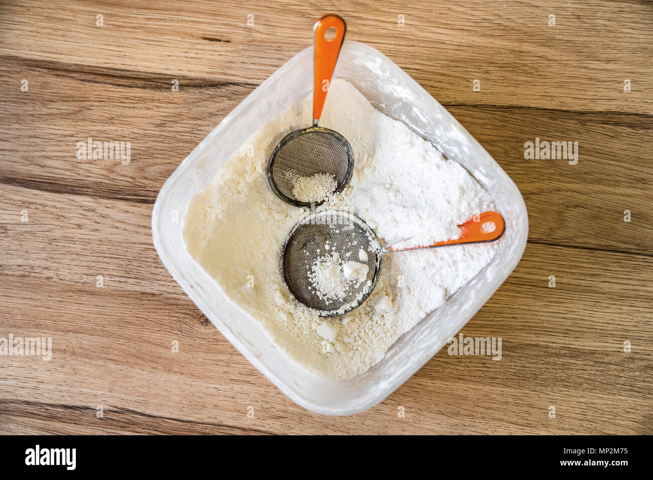 Close up plastic container filled with sugar powder and two sifters in ...