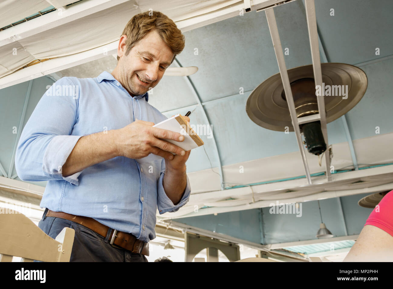 Volos, Greece - May 13th, 201: A greek male waiter is writing an order ...