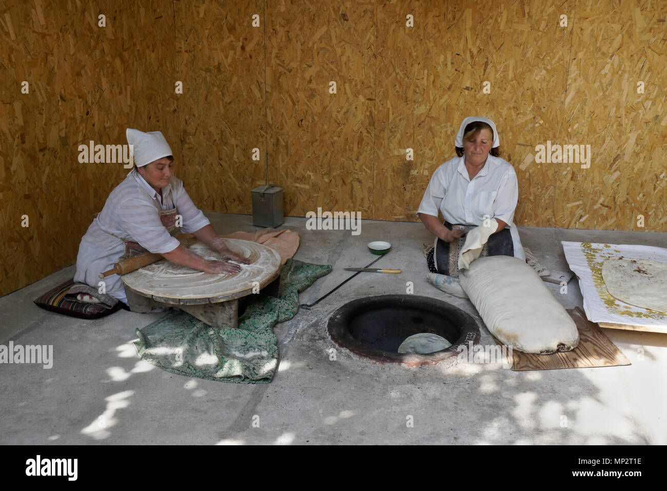 Two women make lavash (a traditional flatbread) by rolling out the ...