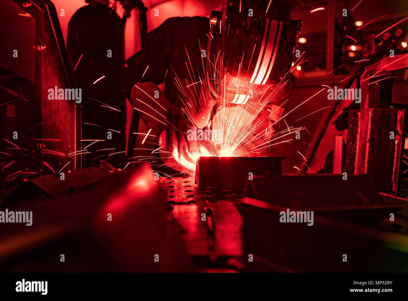 Welder in mask welding metal authentic shooting through red safety ...