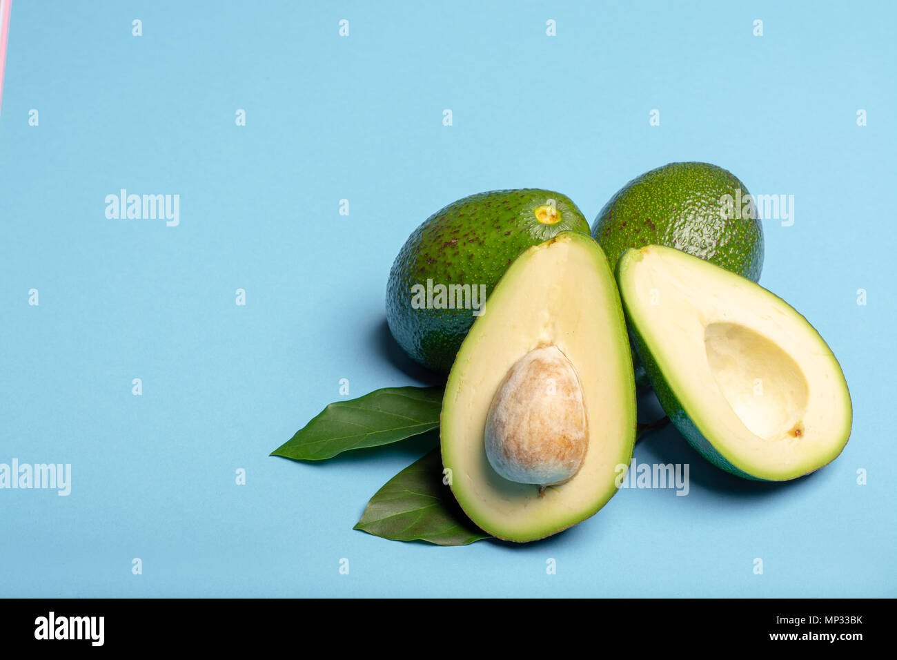 Fresh organic ripe green whole and sliced Fuerte avocado with leaves ...