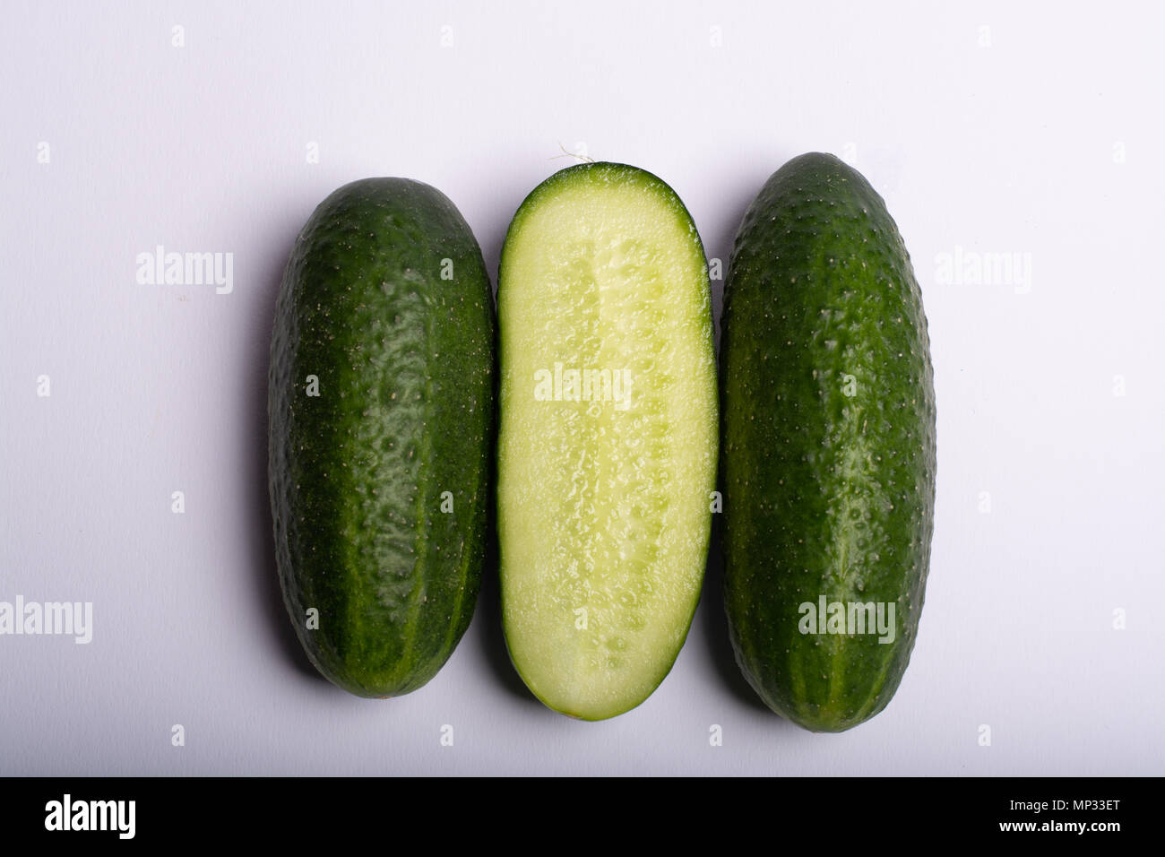 Fresh small green cucumbers whole and sliced close up copy space ...