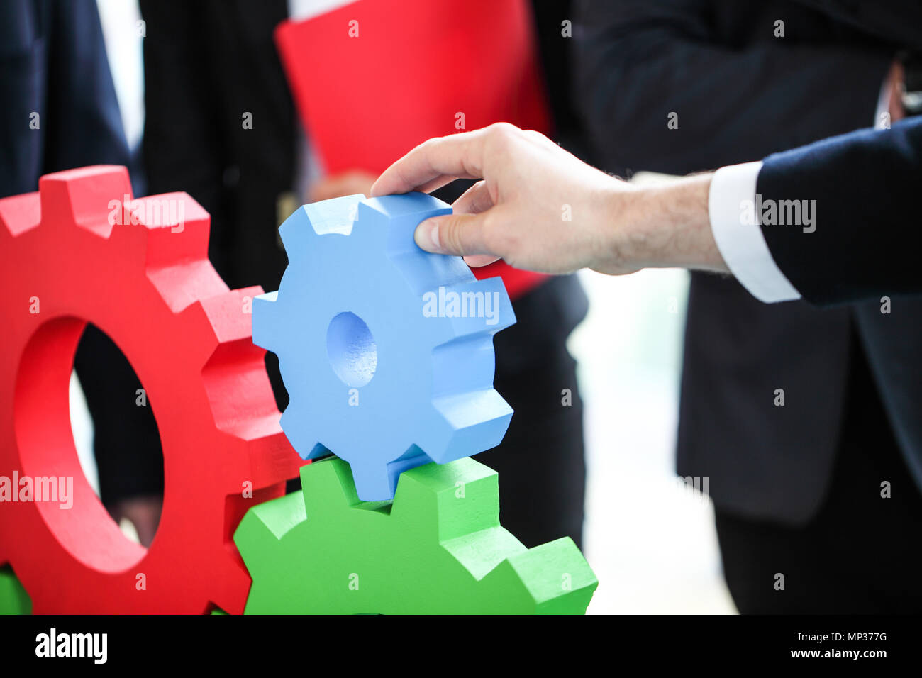 Business people assembling cogwheels, teamwork concept Stock Photo - Alamy