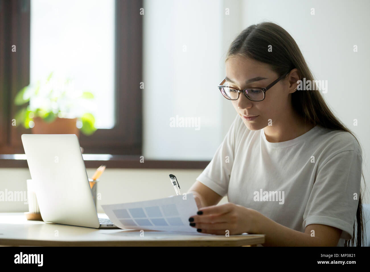 Freelancer working at laptop writing down information Stock Photo - Alamy