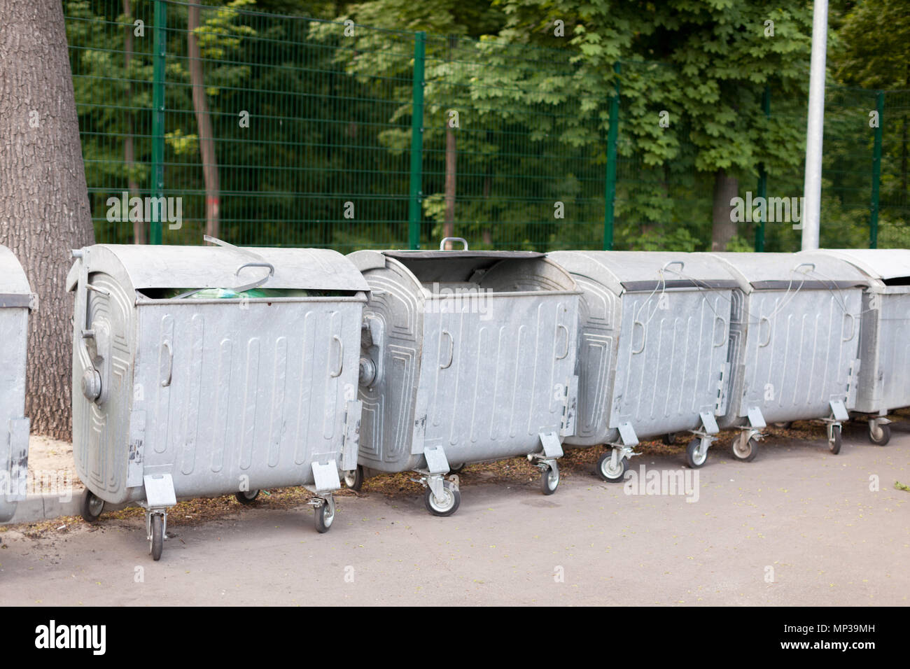 Large metal filled garbage containers on the street standing in a row ...