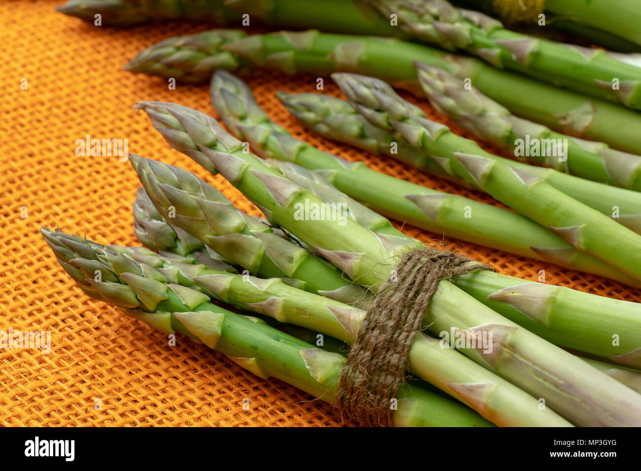 Raw garden asparagus stems. Fresh green spring vegetables on orange ...