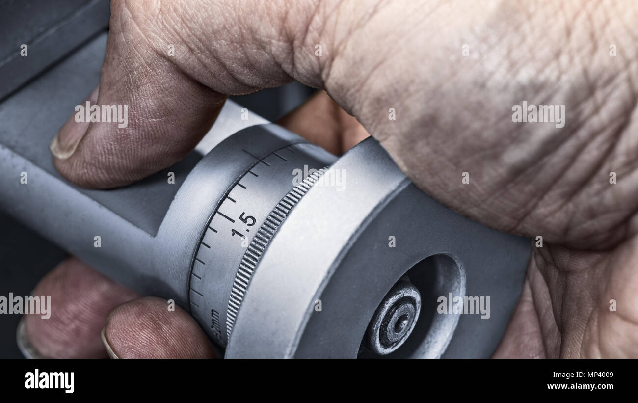 Control knob of machine tool in detail. Close-up of dirty hand on metal ...