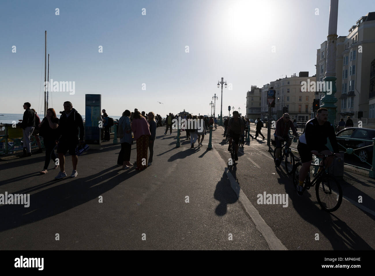 Shadowy pedestrians and cyclists on a busy path on Brighton seafront ...