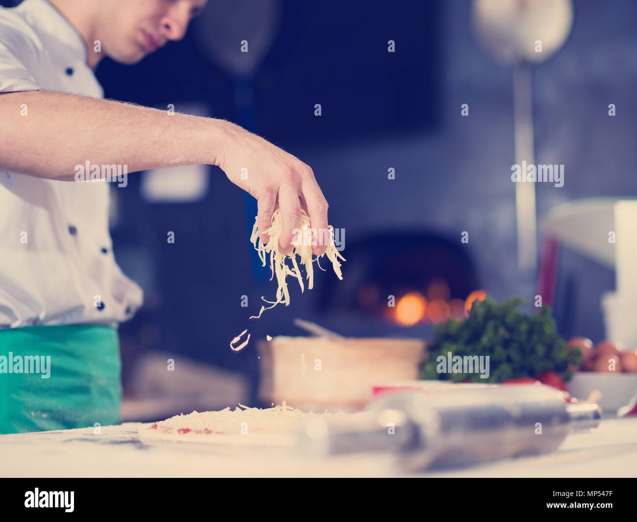 chef sprinkling cheese over fresh pizza dough on kitchen table Stock ...