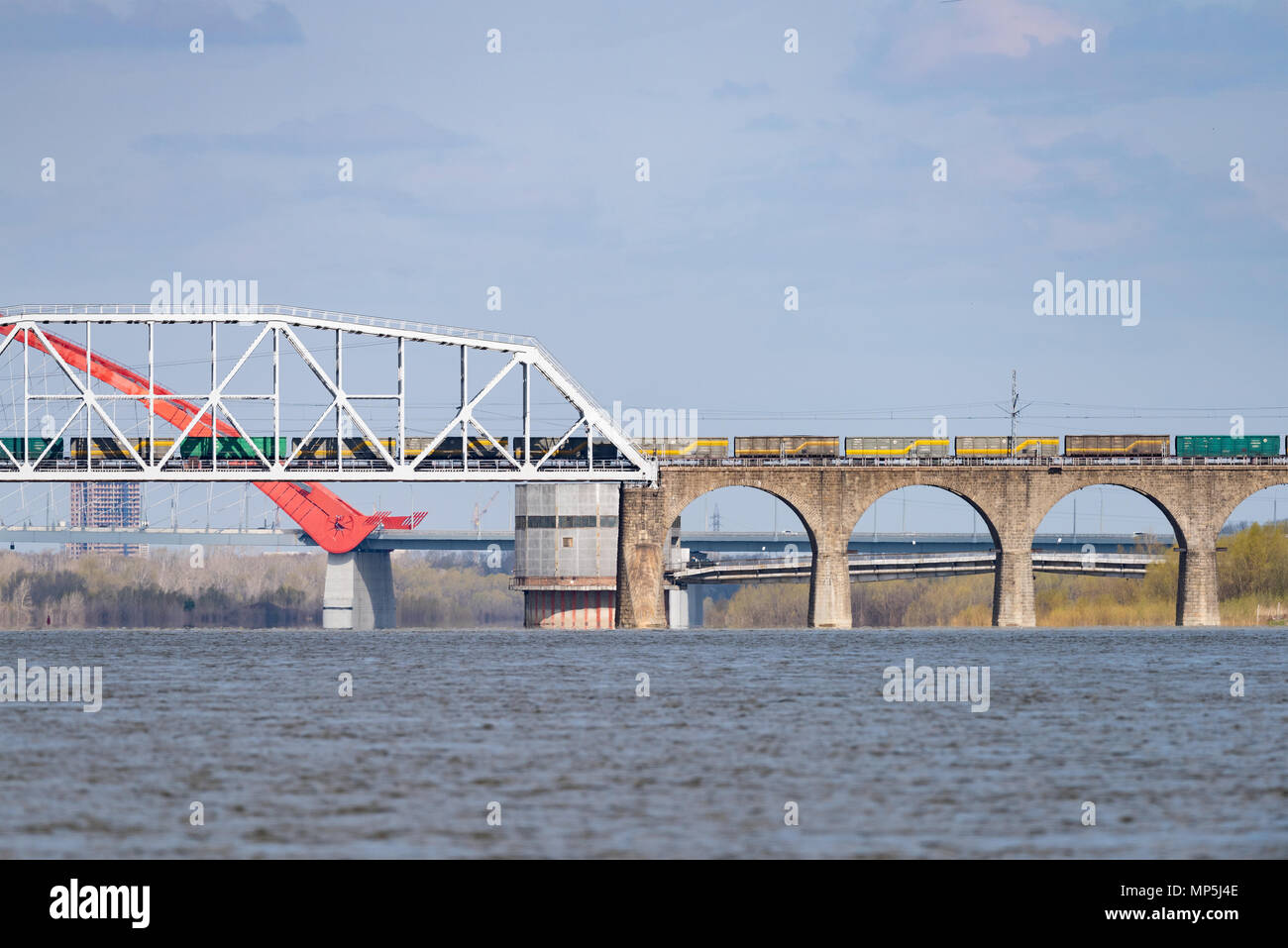 a freight train is driving across a bridge across the river Stock Photo ...