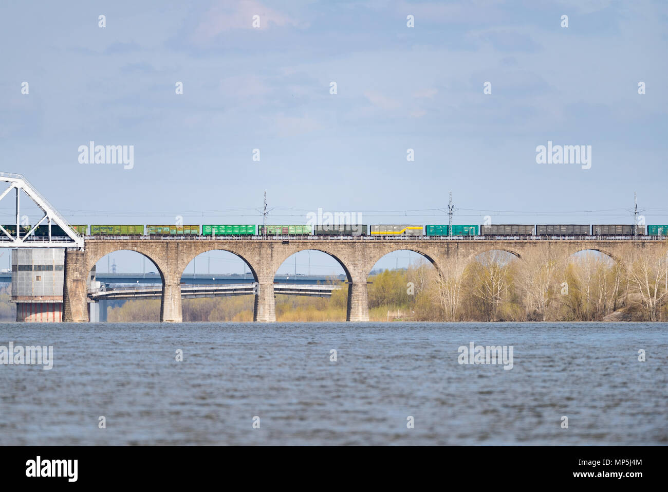 a freight train is driving across a bridge across the river Stock Photo ...