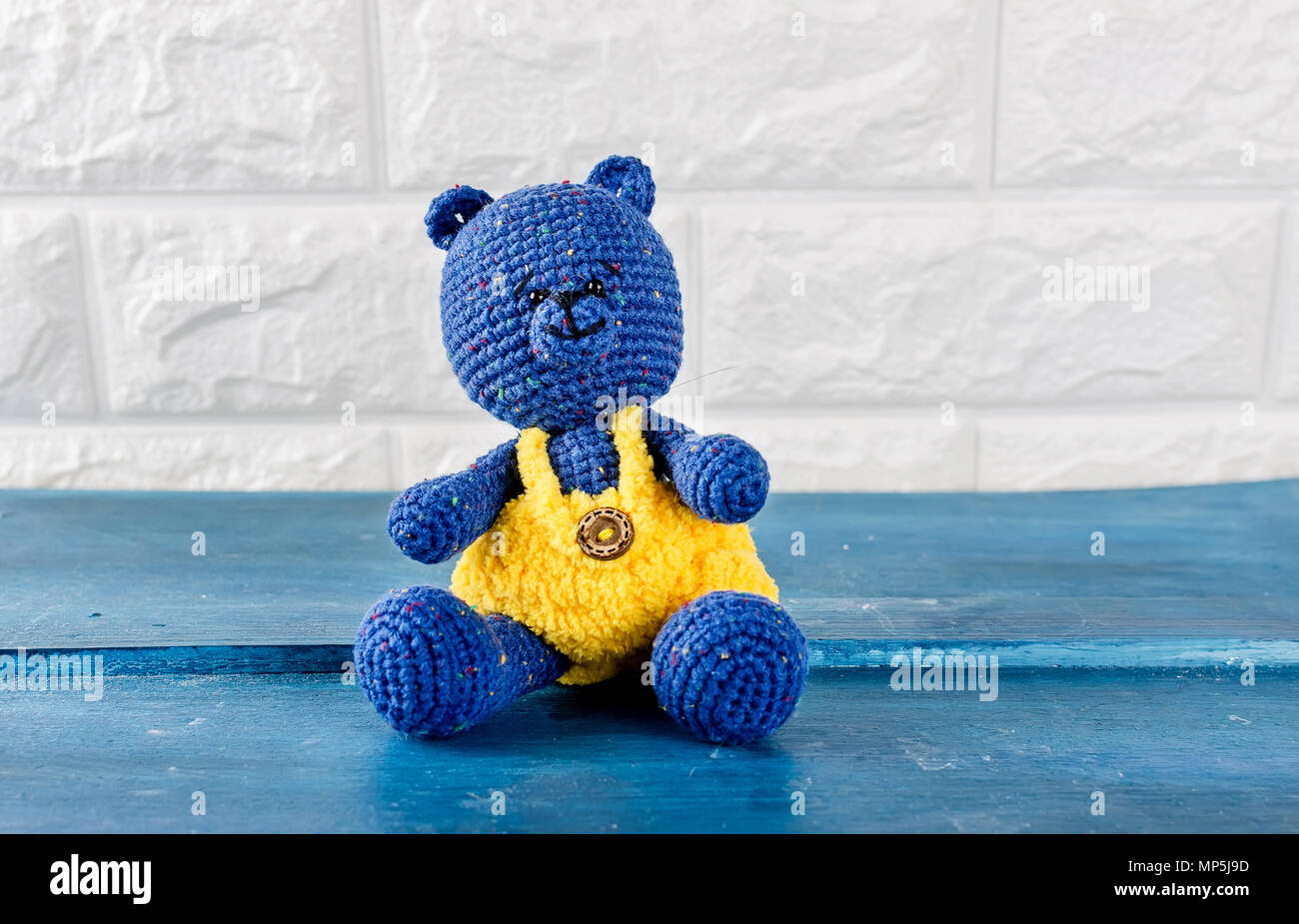 Cute handmade blue bear toy on a brick wall background, copy spase ...