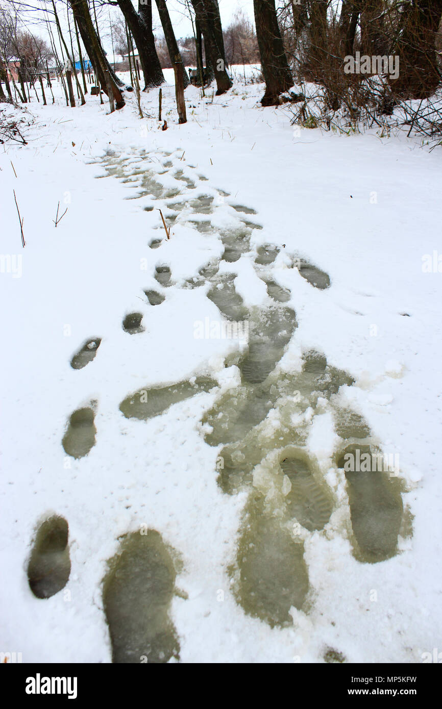 Traces of shoes on snow during the thaw. Footprints on the river ice ...
