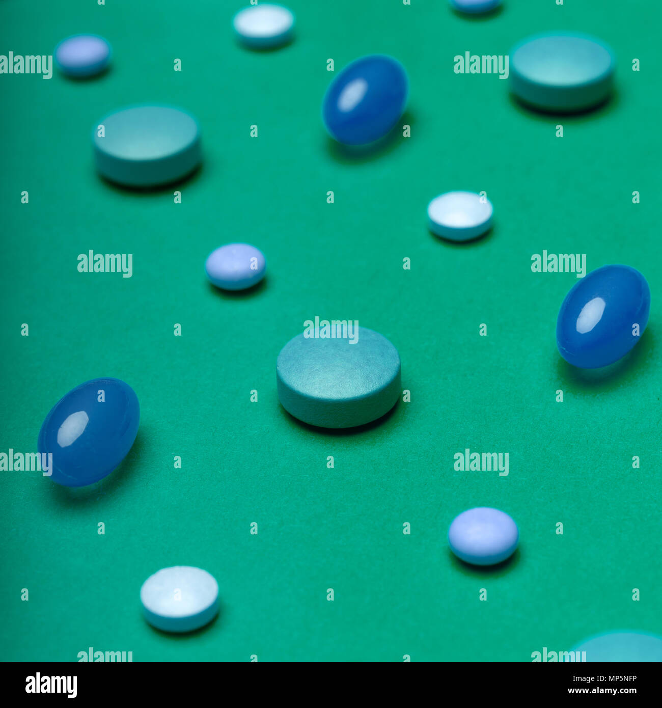 Assortment of various colourful pills green coloured background ...