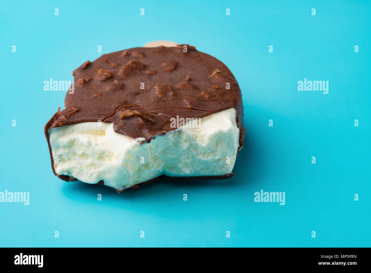 side view chocolate outer ice cream with some bites on a blue ...