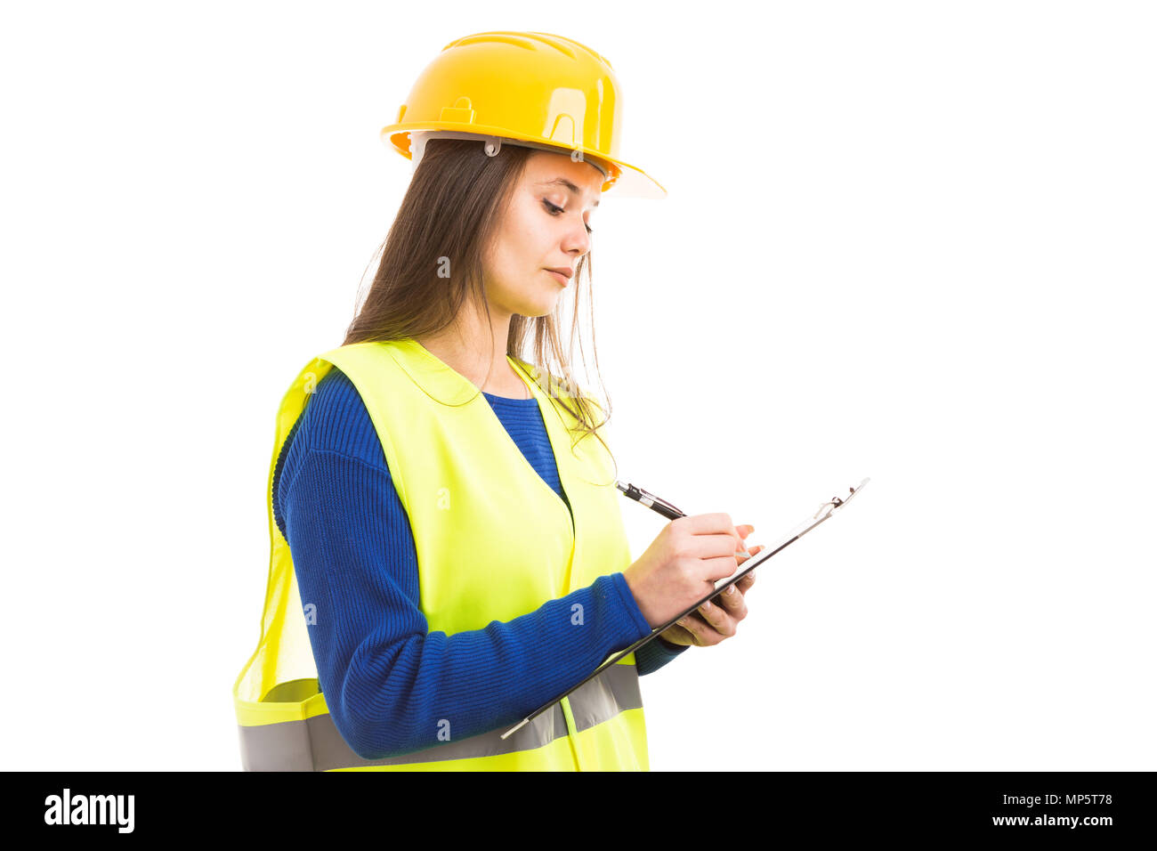 Young female engineer or architect writing on clipboard as busy working ...