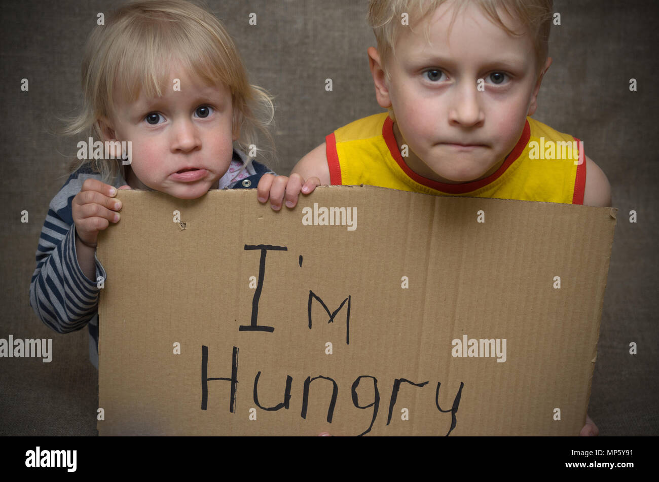 A hungry boy and a girl with a cardboard tablet with the inscription I ...