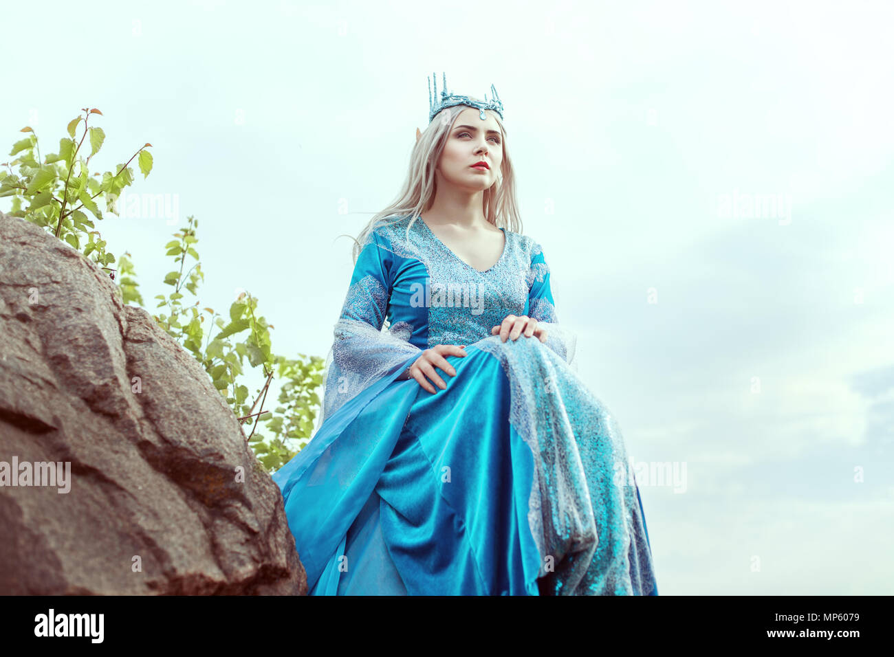 Beautiful elf woman in a blue dress is sitting on the mountain Stock ...