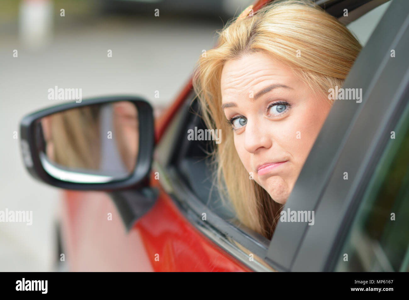 Cute, young blue-eyed driver girl looking through window and asking for ...