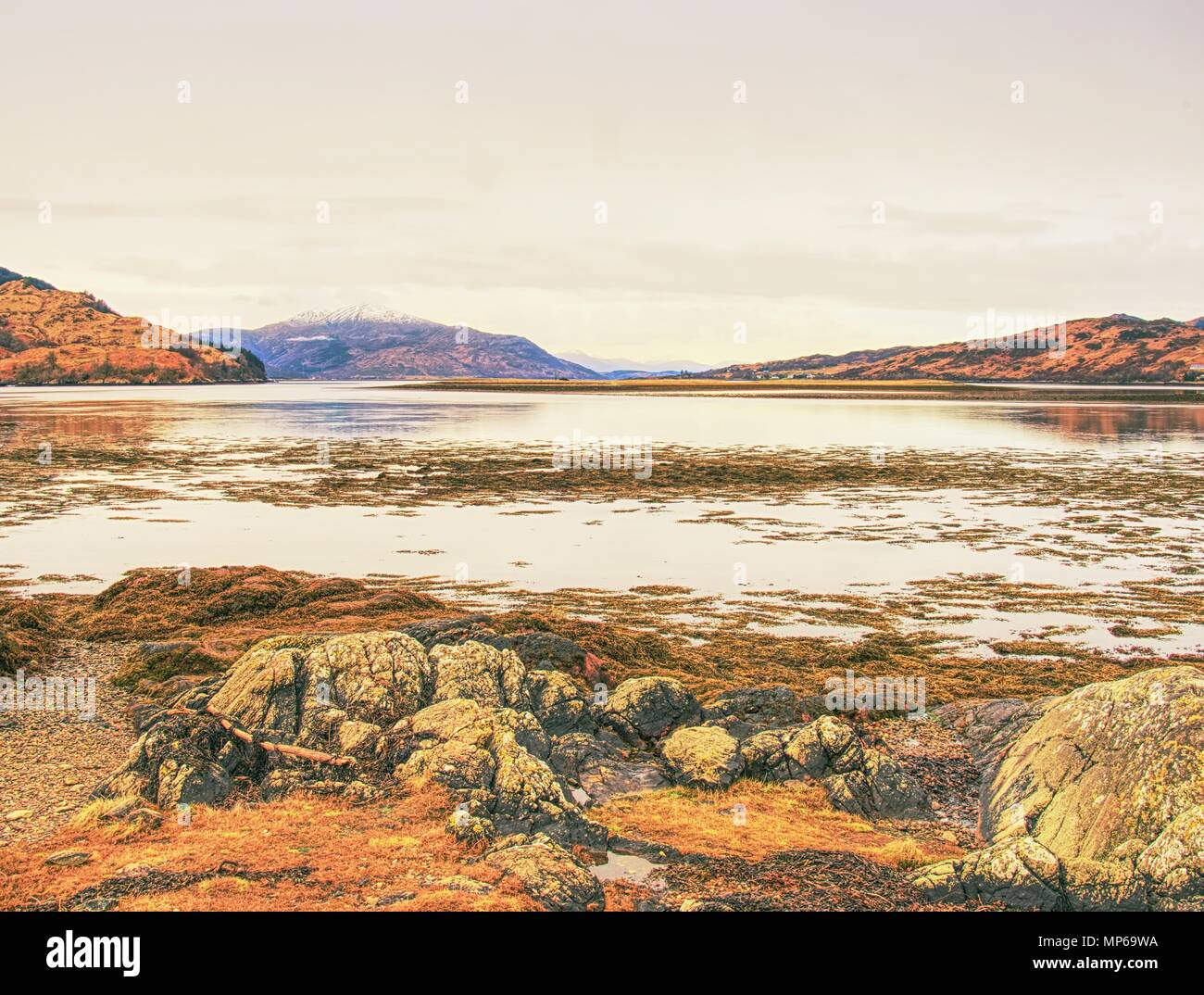 Evening rocky shore with sea water and large cracked rocks with erosion ...