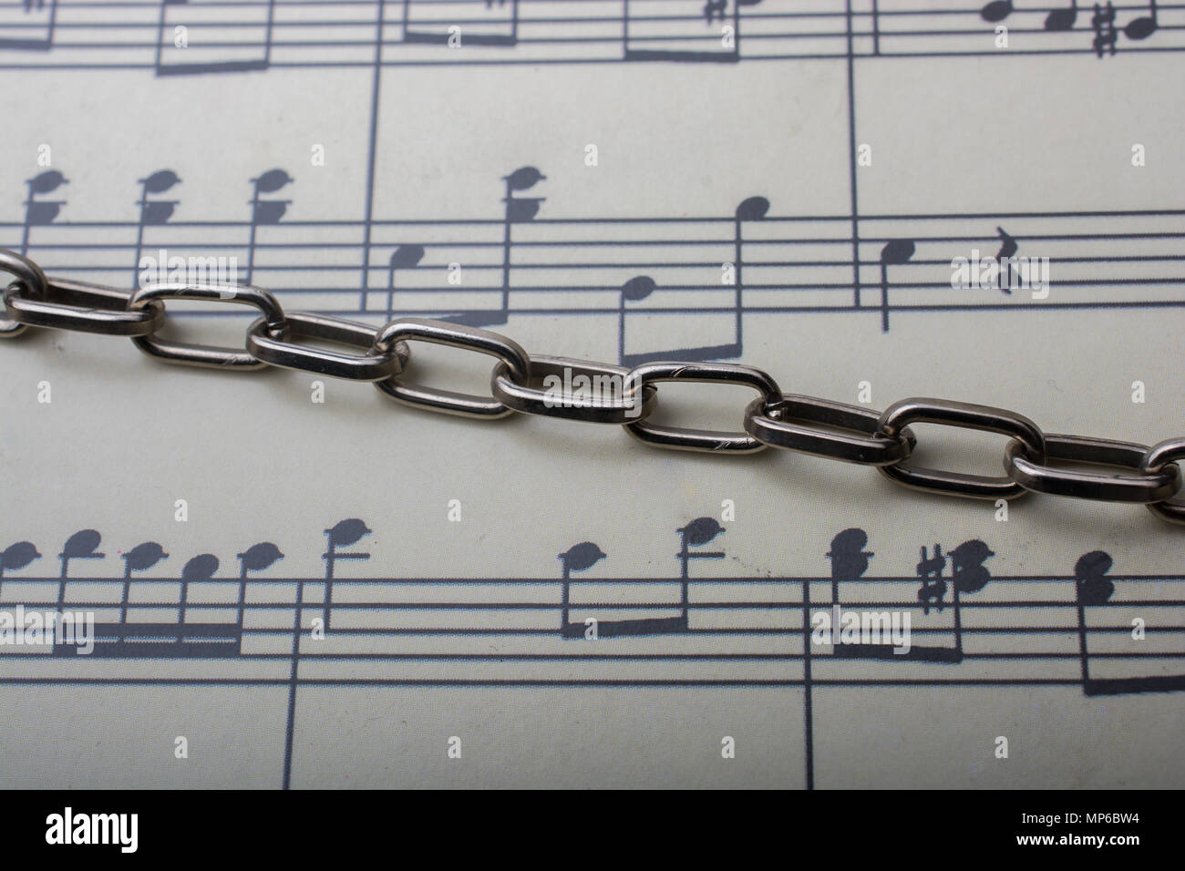 Metal chain placed on a paper with musical notes Stock Photo - Alamy