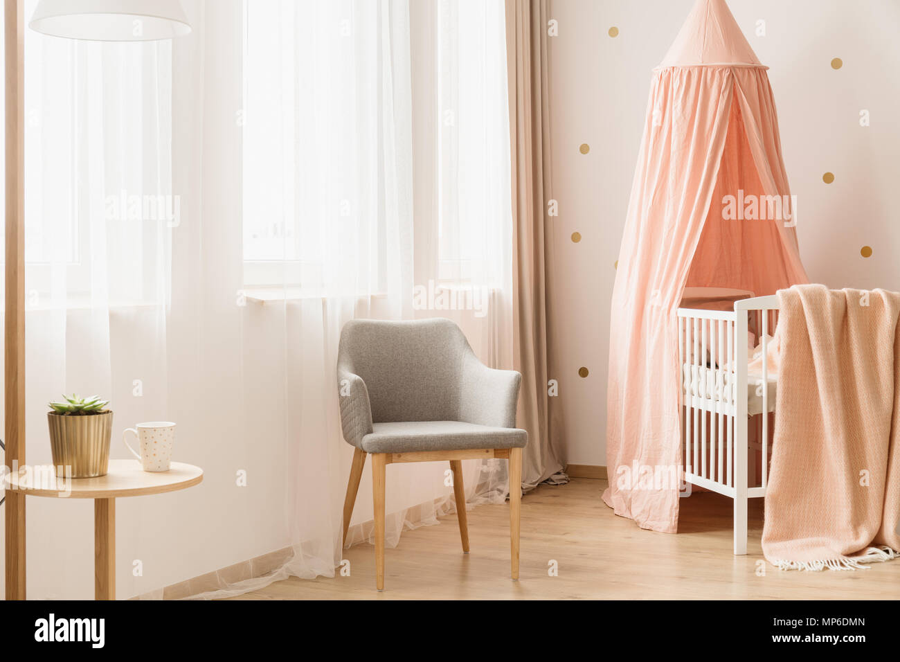 Wooden crib with dirty pink canopy standing in bright nursery room ...