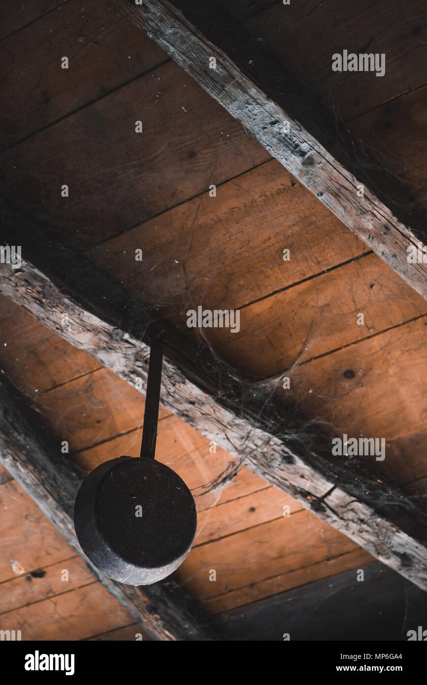Old frying pan covered in spider web hanging from the ceiling in an old ...