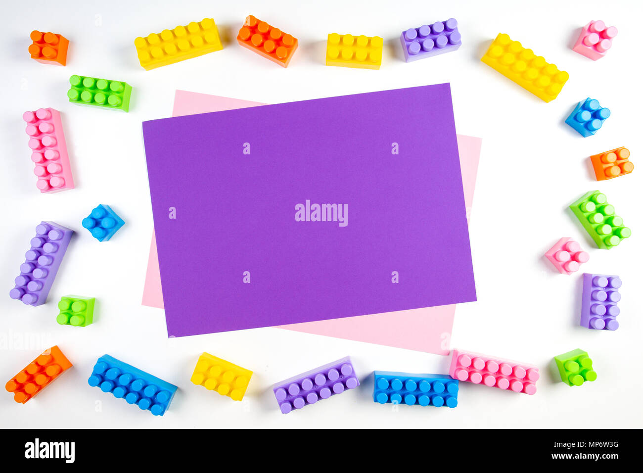 Colorful plastic construction blocks frame with violet blank card on ...