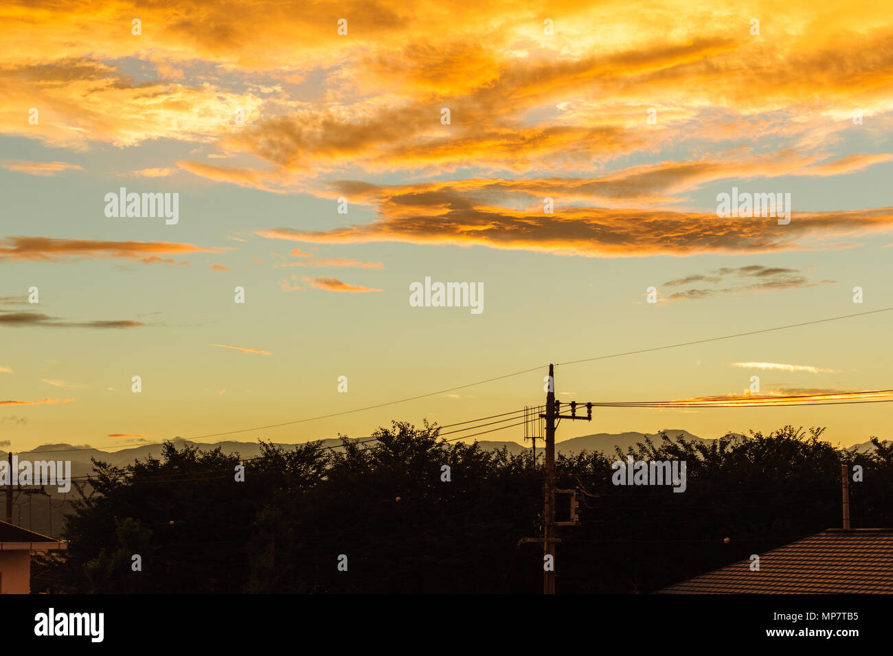Glorious golden cloud in beautiful blue sky at dusk. With houses roof ...