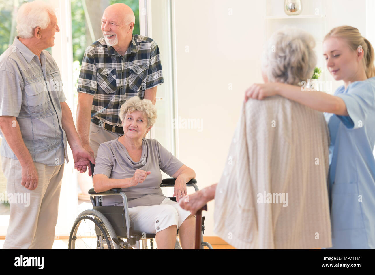 Nurse giving a blanket to patient and elderly man supporting disabled wife in a wheelchair Stock ...