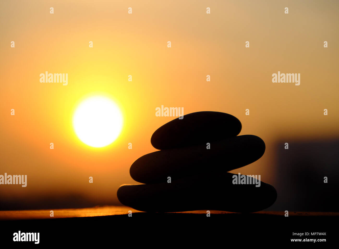 Amazing shape of stack of pebble on yellow sun background at sunrise ...