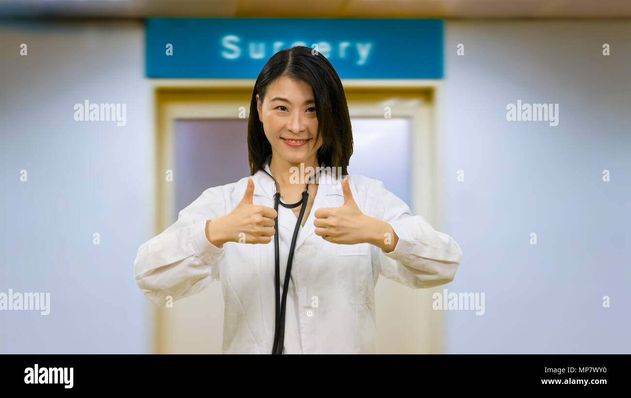 Chinese female doctor in hospital surgery giving thumbs up gesture ...