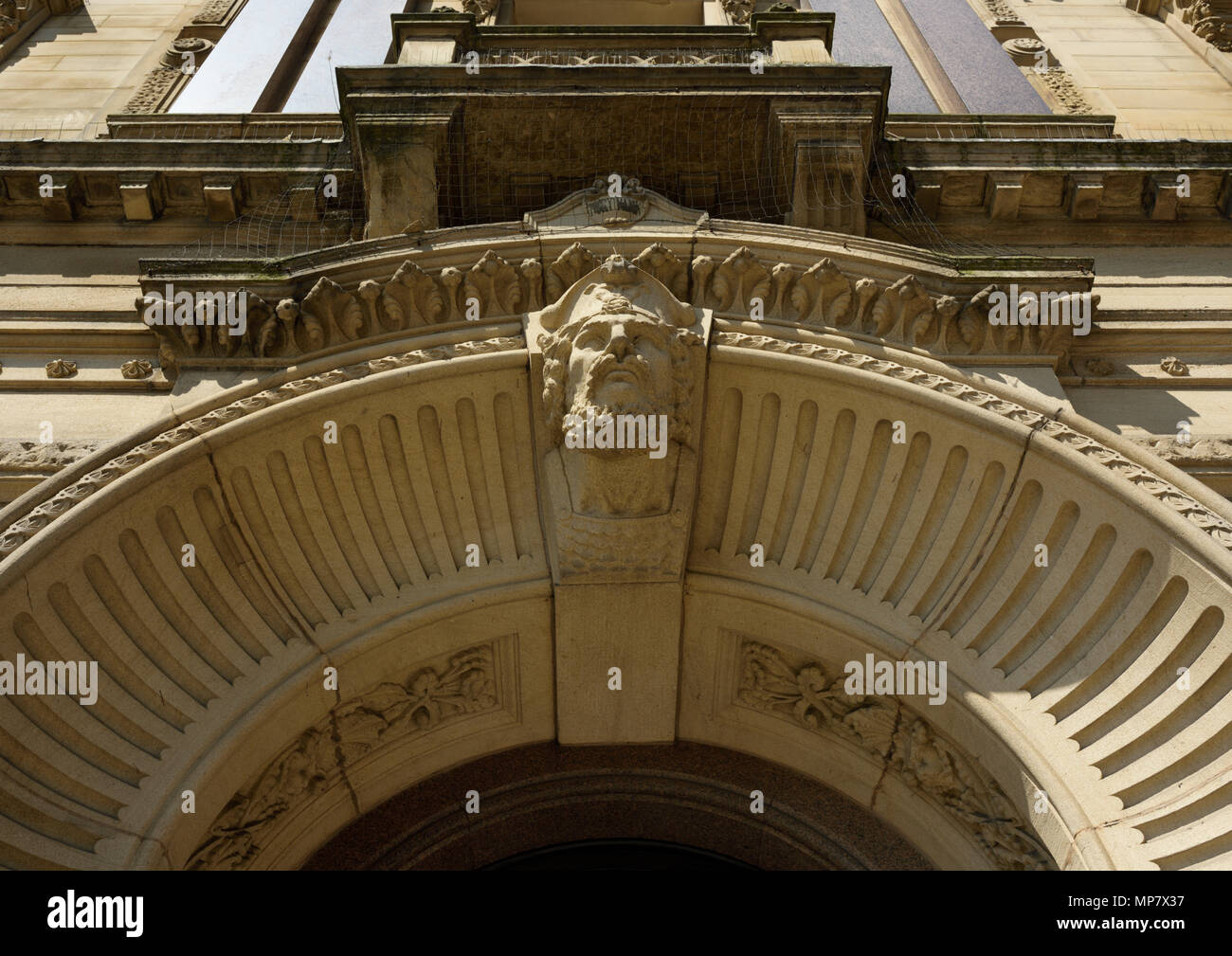 Ribbed stone arch with grotesque head of plutus keystone in old bank ...