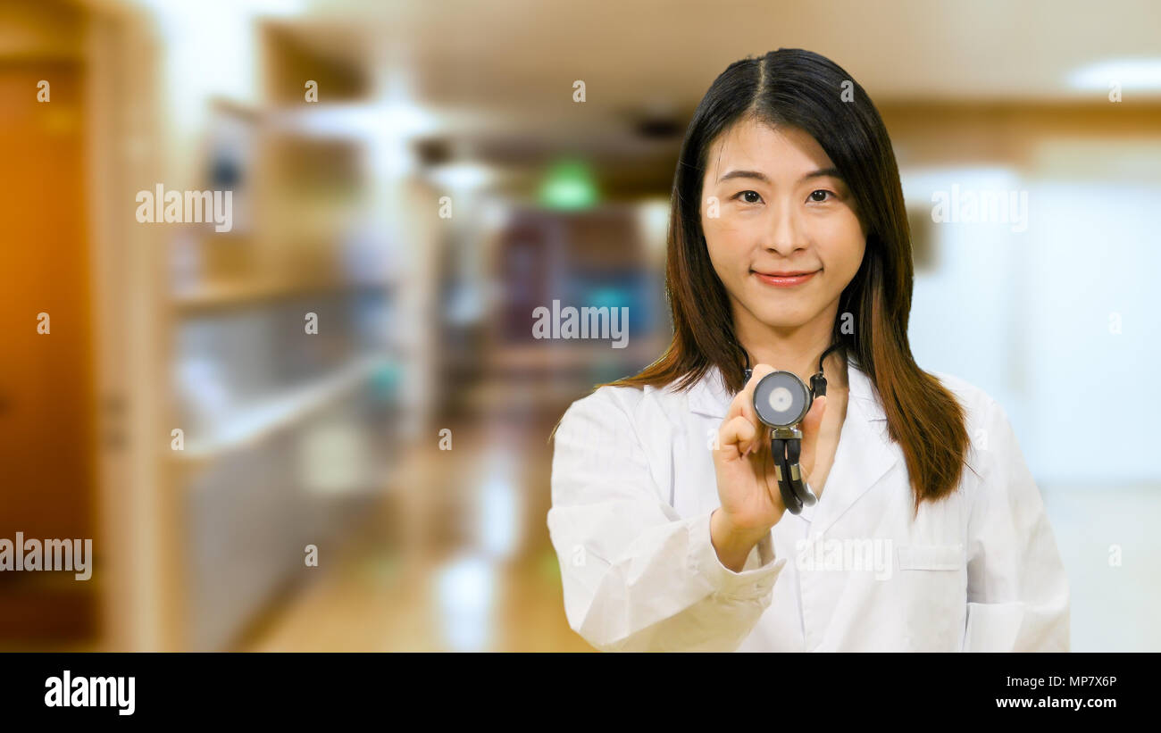 Chinese female doctor in hospital holding out stethoscope, looking at ...
