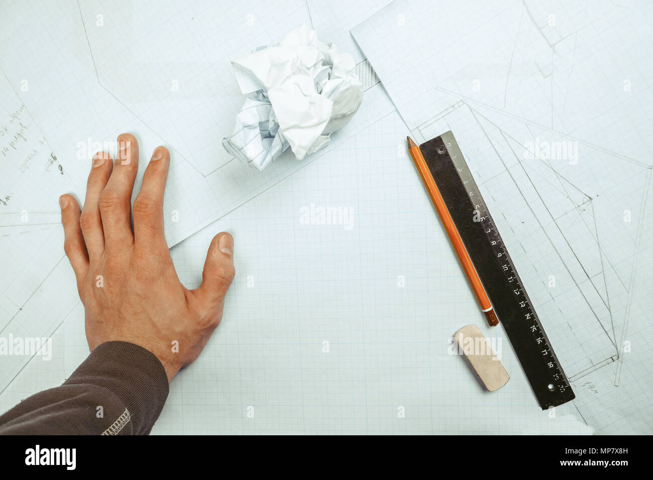Close-up of human hand with pencil over blueprints with sketches of ...