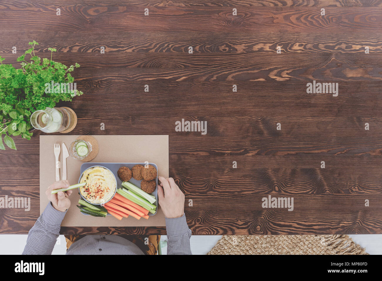 Man sitting beside rustic table eating hummus and falafel Stock Photo ...