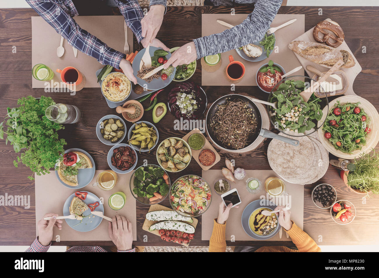 Four people having dinner, sitting at wood table Stock Photo - Alamy