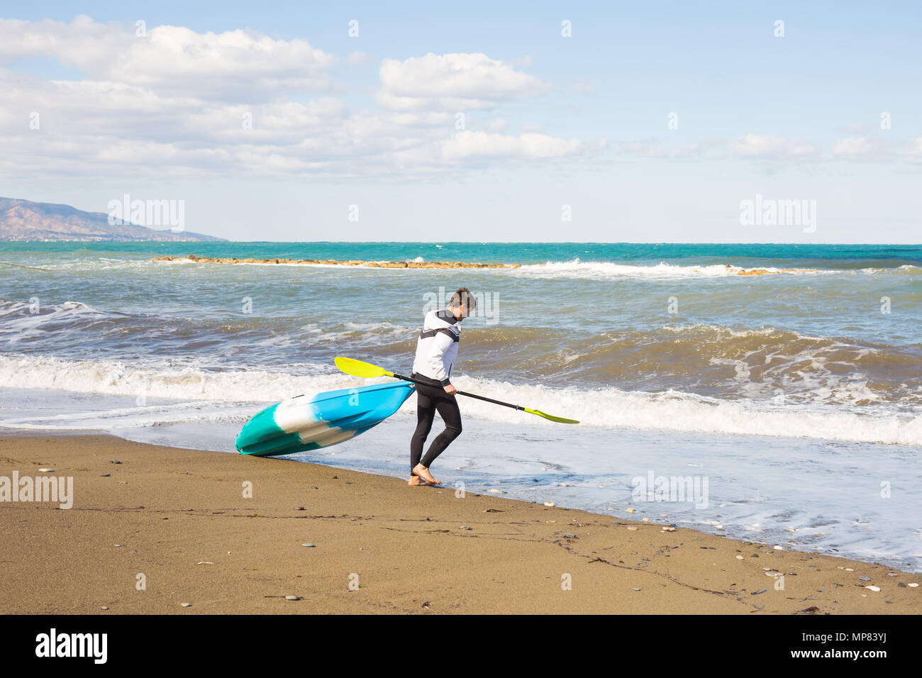 Man carrying his kayak along the shore Stock Photo - Alamy