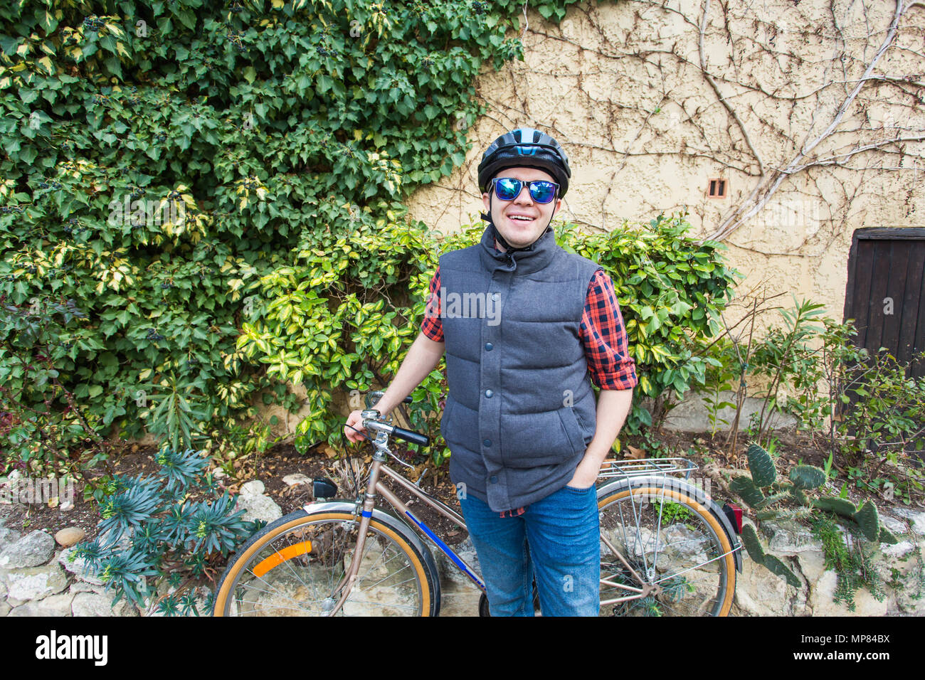 Handsome guy cyclist in cycling clothes and helmet posing near bicycle ...
