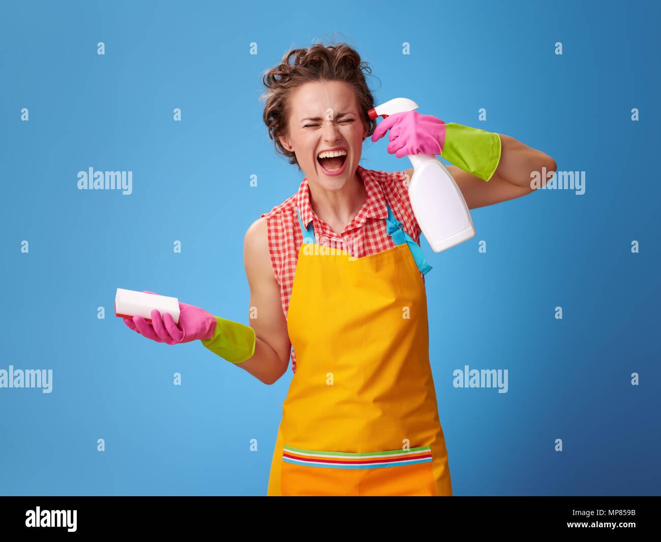 Big cleaning time. stressed young housewife in a yellow apron with ...