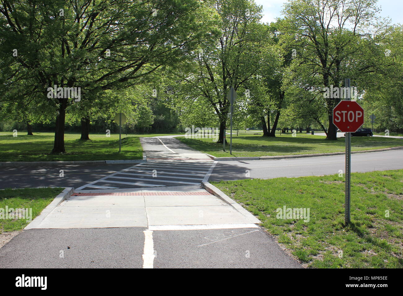 Intersection of a bike and walking trail with a car road on a sunny day ...