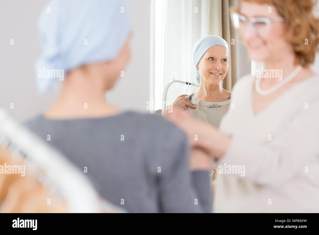 Sick woman suffering from cancer and her friend picking new outfit ...