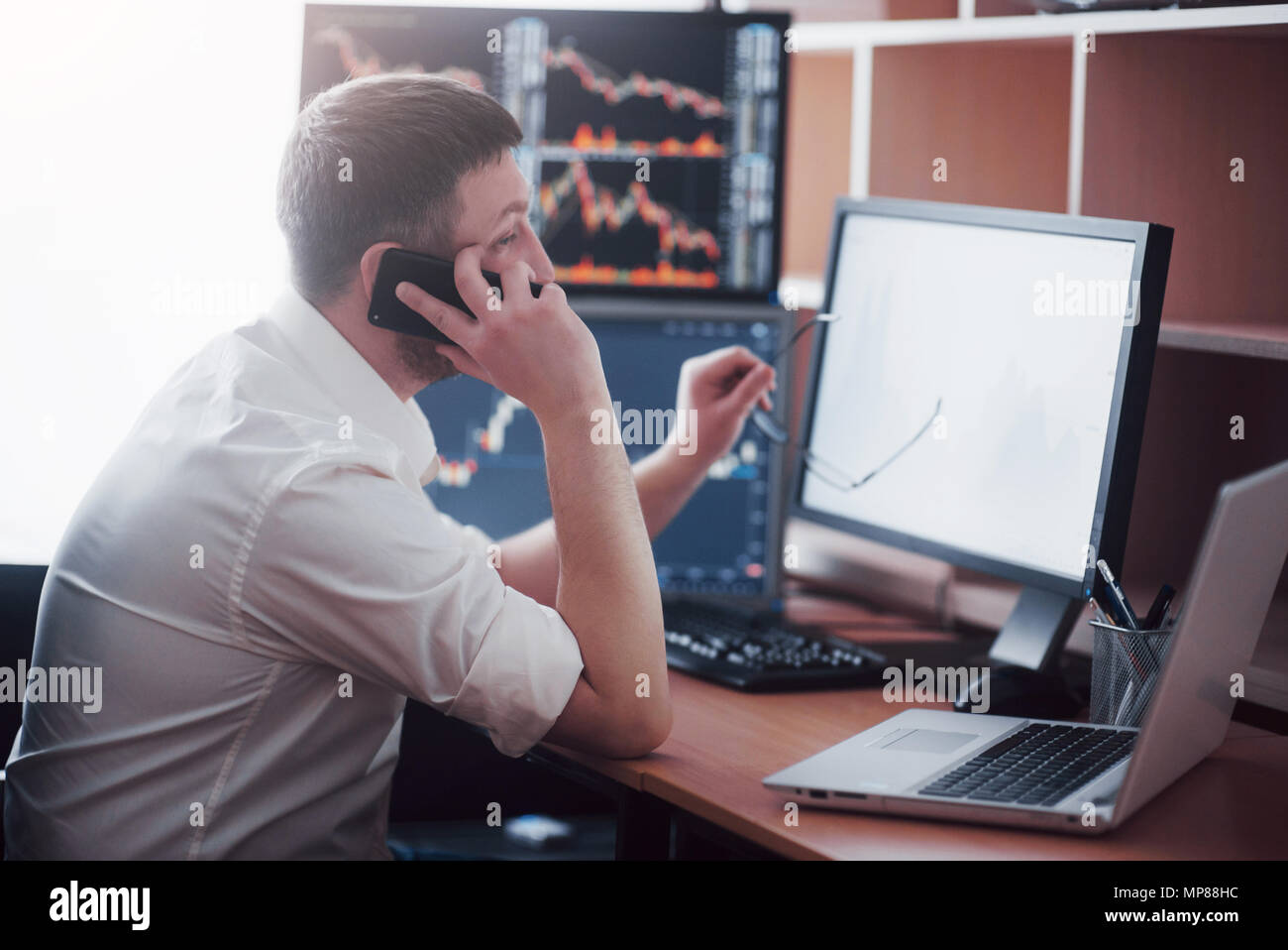 Stockbroker in shirt is working in a monitoring room with display ...