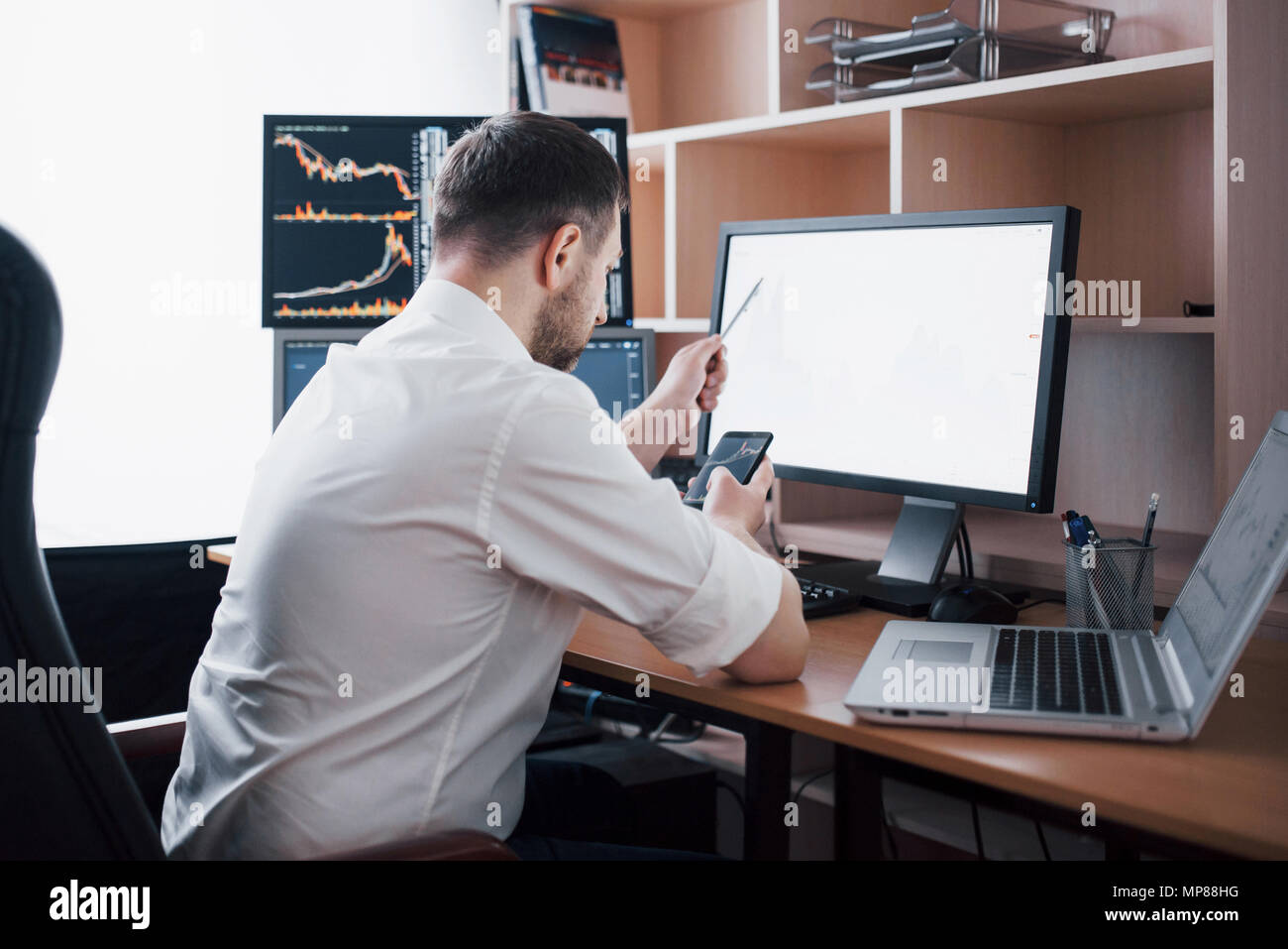 Stockbroker in shirt is working in a monitoring room with display ...