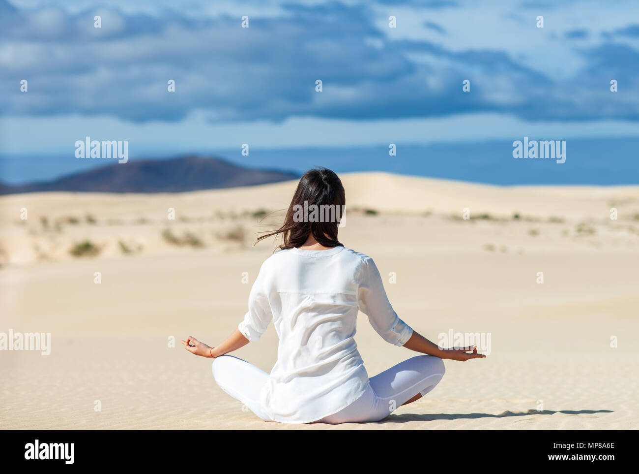 Back view of young woman meditating in Lotus Pose in desert. Padmasana ...