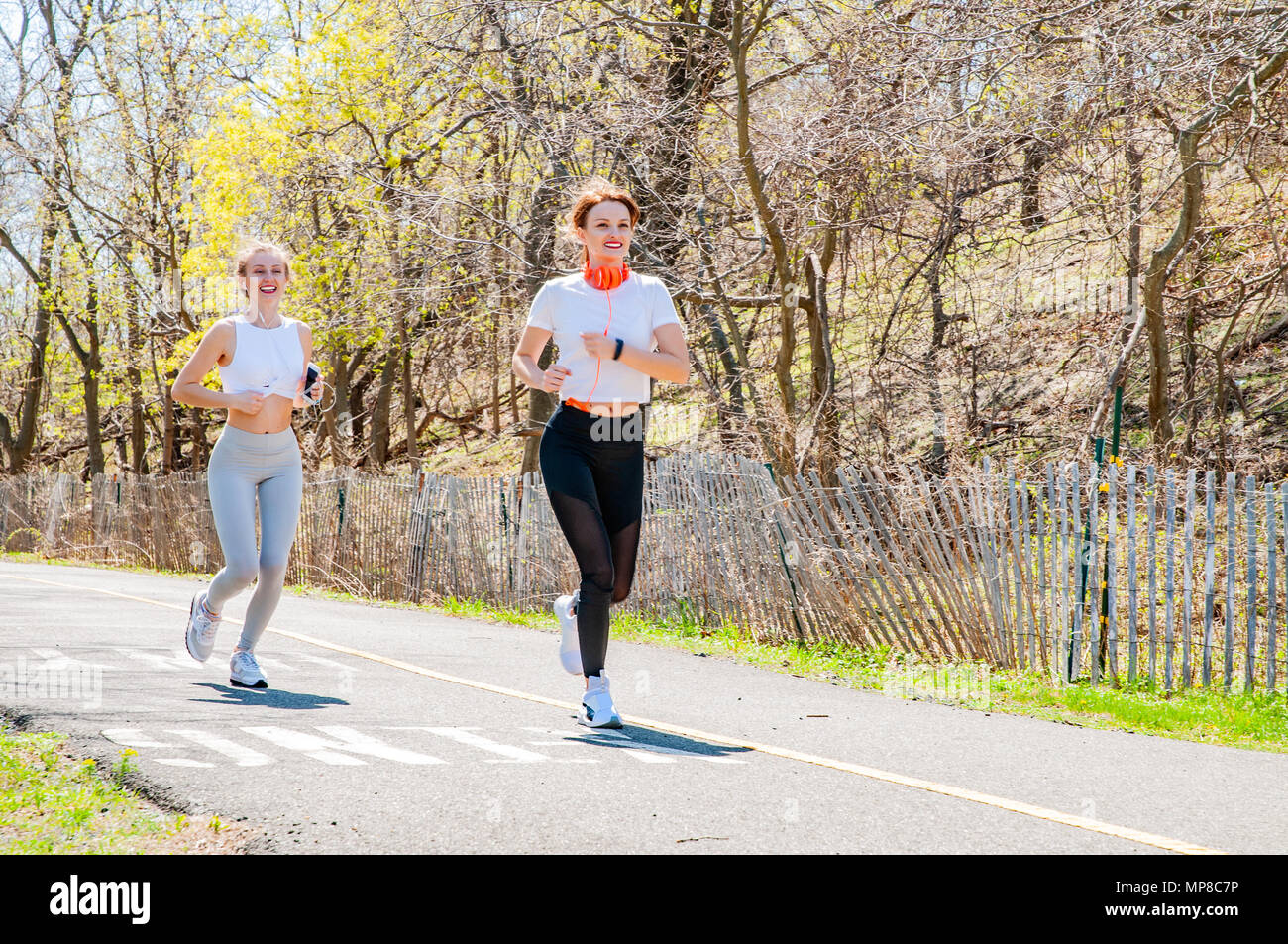 Two happy sporty girls running in the park. Female fitness training ...